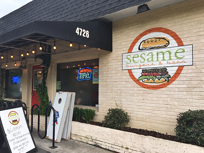 Sesame Burgers & Beer's inviting entrance features string lights and a painted burger logo, promising no-frills deliciousness inside.
