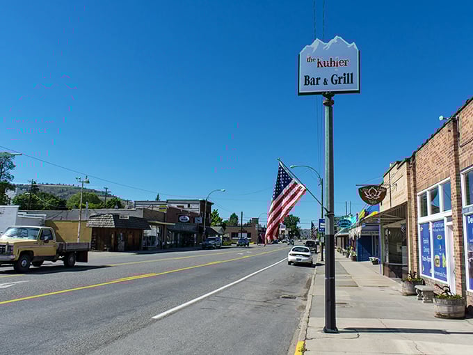 The Kuhler Bar & Grill sign stands as a friendly sentinel on Tonasket's main drag, where conversations flow as freely as the nearby river.