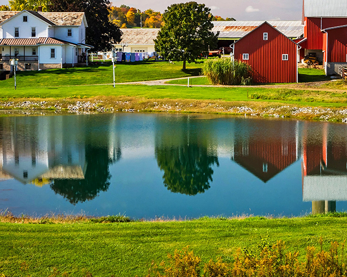 Reflections of a simpler life. The peaceful pond mirrors red barns and white farmhouses in perfect countryside harmony.