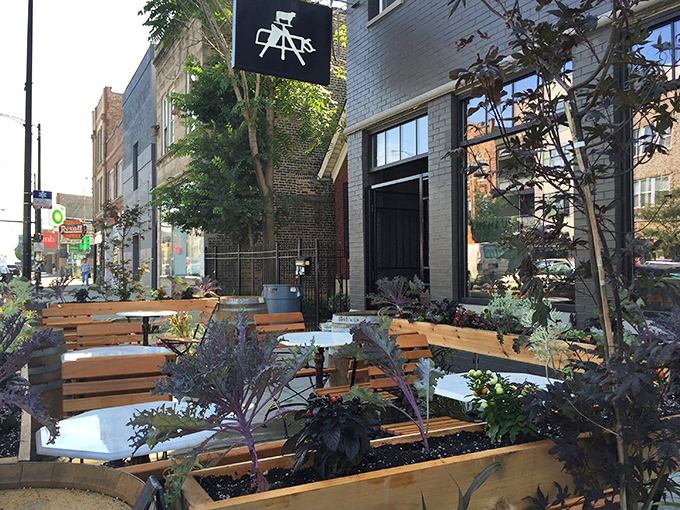 A sidewalk oasis in the city, where plant life and wooden benches invite you to linger before the main event inside.
