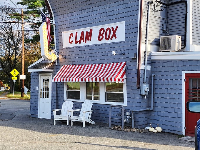 White Adirondack chairs welcome visitors to relax outside the Clam Box, where the iconic sign promises legendary fried seafood inside.