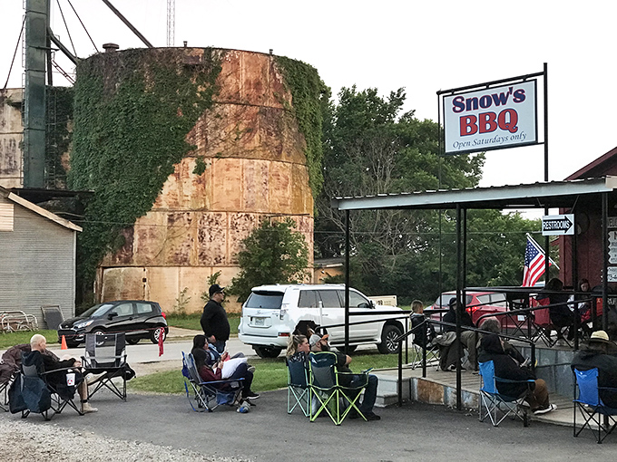 Patrons bring chairs while waiting at Snow's BBQ. The iconic water tower and American flag showcase its small-town Texas charm.