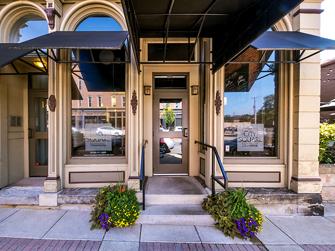 The elegant entrance to City Square Steakhouse welcomes hungry visitors with classic architecture and colorful flower planters in downtown Wooster.
