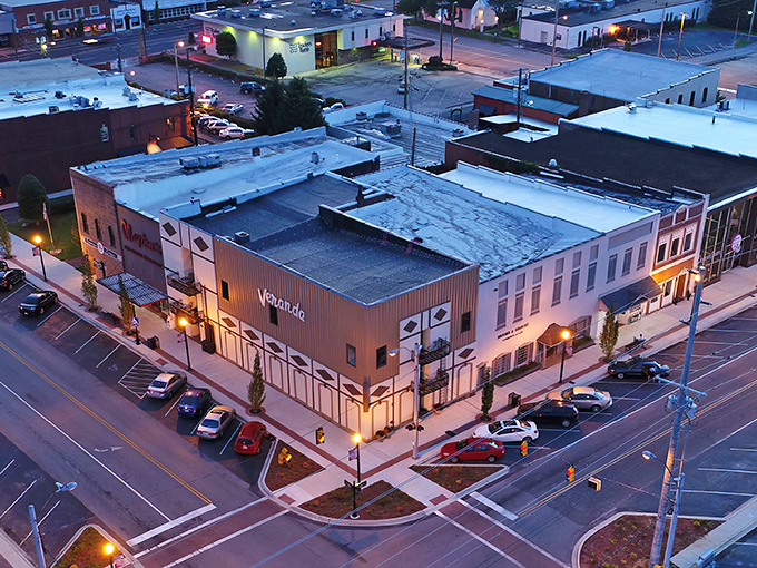 Evening lights illuminate a revitalized main street where your dollar stretches like warm taffy.