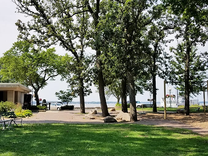 Towering trees stand sentinel over the shoreline, offering shade and serenity for those wise enough to pause and enjoy the view.