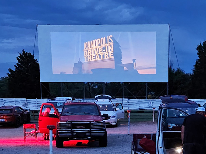 Movie magic comes alive as the Kanopolis Drive-In logo illuminates the twilight, while trucks and cars create personal viewing lounges in the Kansas dusk.