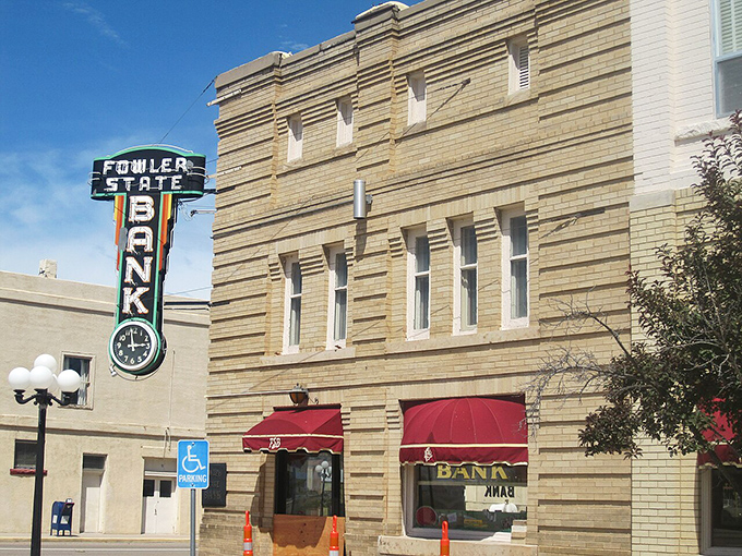 The historic Fowler State Bank building stands as a testament to permanence in a changing world, its vintage neon sign a beacon of small-town financial stability.
