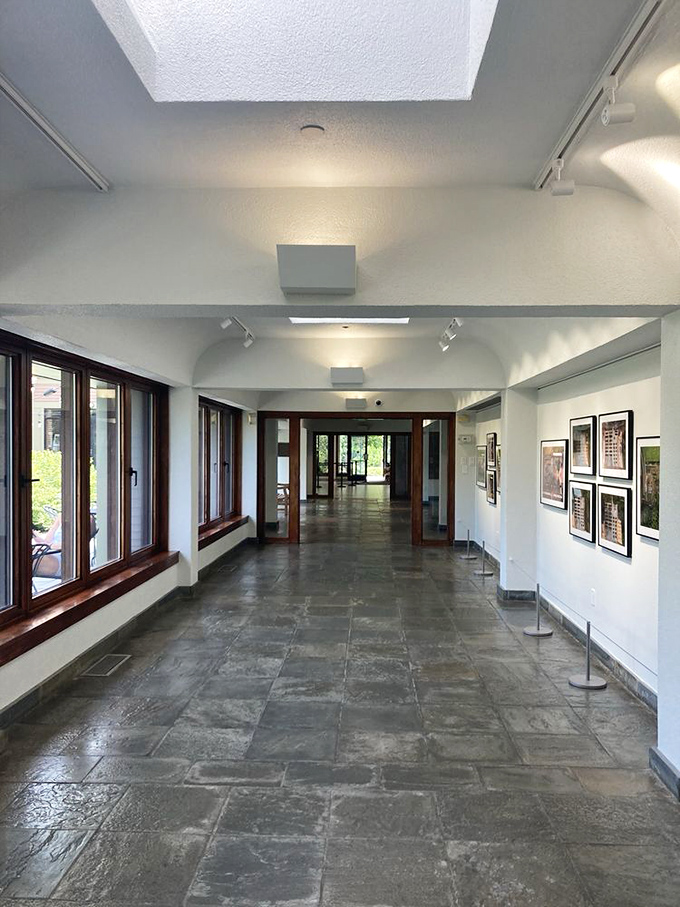 This serene gallery hallway serves as both palate cleanser and promise&mdash;a neutral space between colorful garden rooms that whispers, "The best is yet to come."