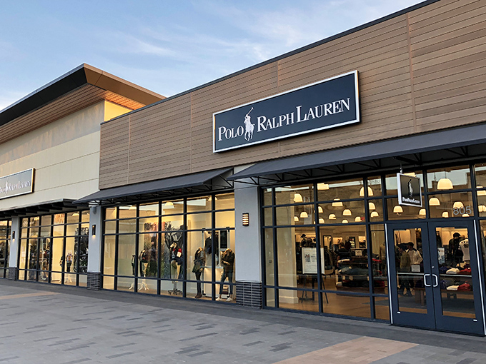 The Polo Ralph Lauren storefront glows like a beacon of preppy promise, where that little horse emblem becomes suddenly affordable.