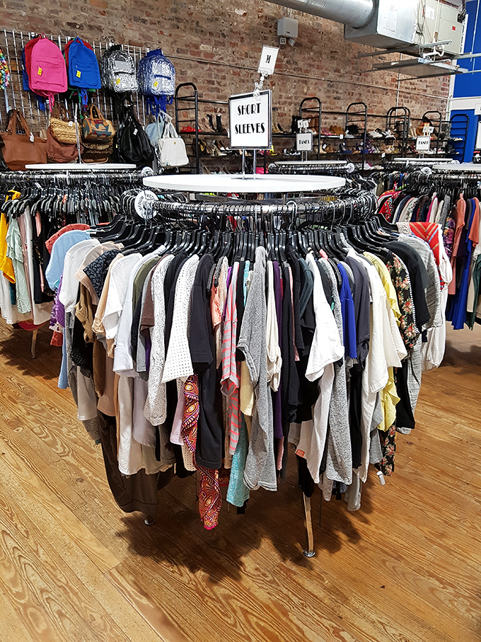 The circular rack of short-sleeved tops offers a kaleidoscope of patterns and colors against the rustic backdrop of exposed brick walls.