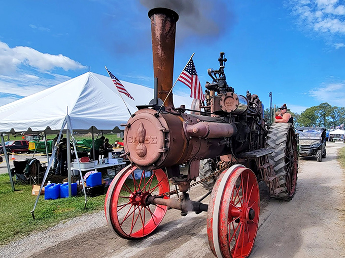 Iron giant taking a breather. This magnificent steam tractor's gleaming red wheels have seen more American history than a Ken Burns documentary.