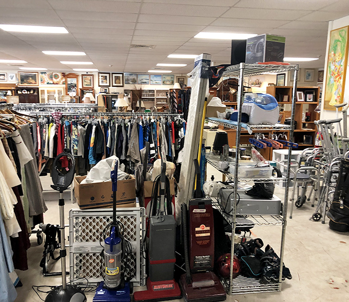 The organized chaos of thrifting at its finest&mdash;vacuum cleaners standing guard over clothing racks like sentinels of domestic history.