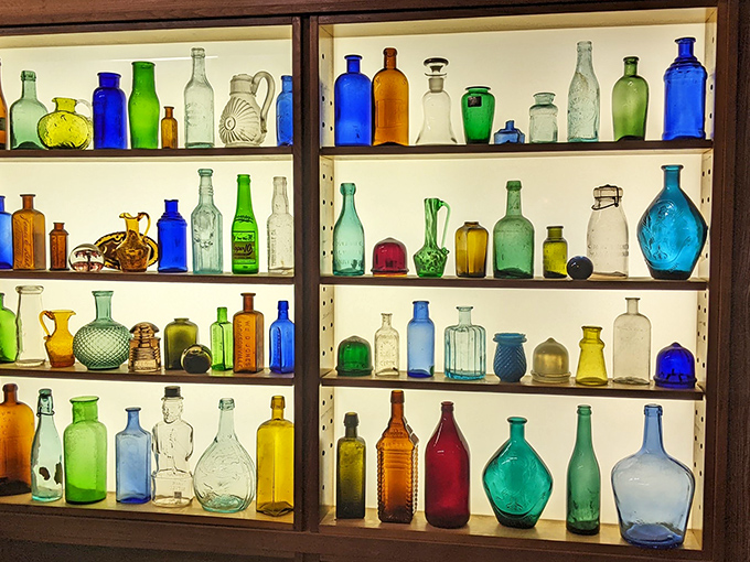 Sunlight transforms this vintage bottle collection into a stained-glass symphony. Each colored vessel once held someone's tonic, soda, or perhaps something stronger.