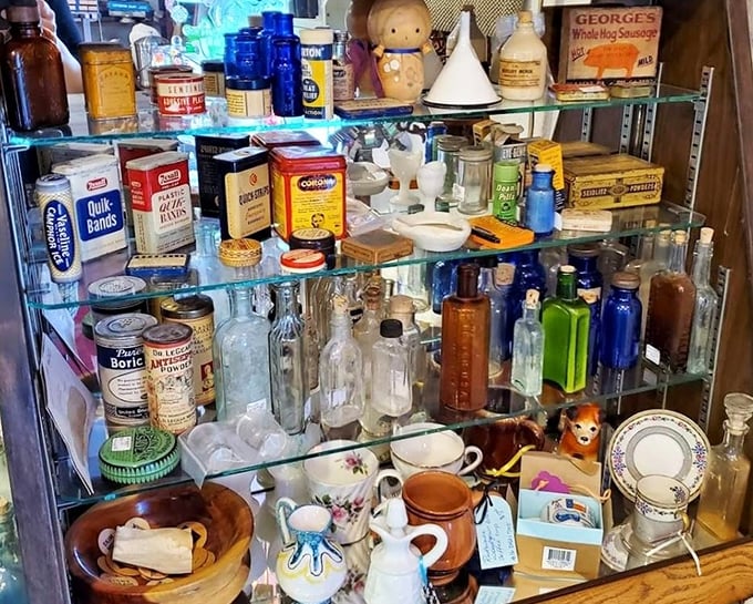 Glass shelves overflow with cobalt bottles, vintage tins, and ceramic treasures&mdash;a pharmacy time capsule that predates your grandparents' medicine cabinet.