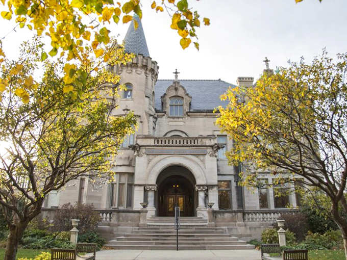 Framed by golden autumn leaves, the mansion's grand entrance beckons visitors through a portal where Minnesota practicality meets Scandinavian splendor.