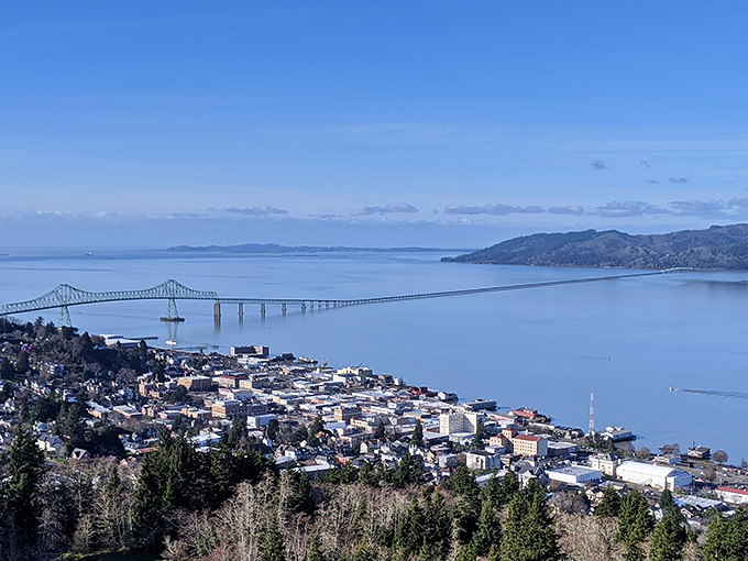 Perched high above the Columbia River, this panoramic view showcases Astoria's perfect positioning between river and sea, connected by the graceful span of the Megler Bridge.