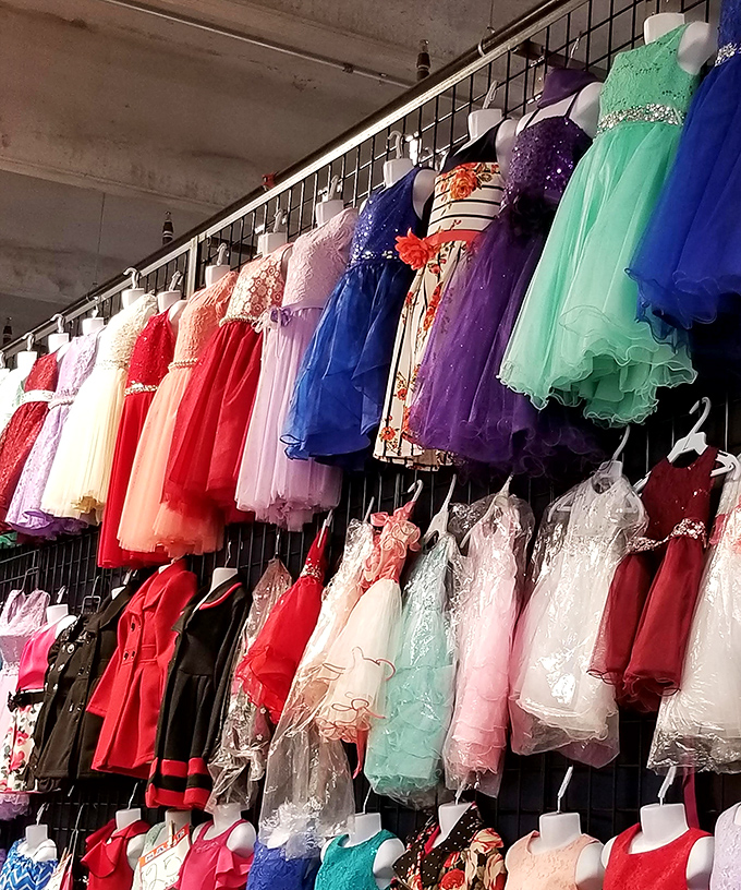 A rainbow explosion of formal wear awaits young dreamers, where quincea&ntilde;era dresses and party frocks hang like colorful promises. 
