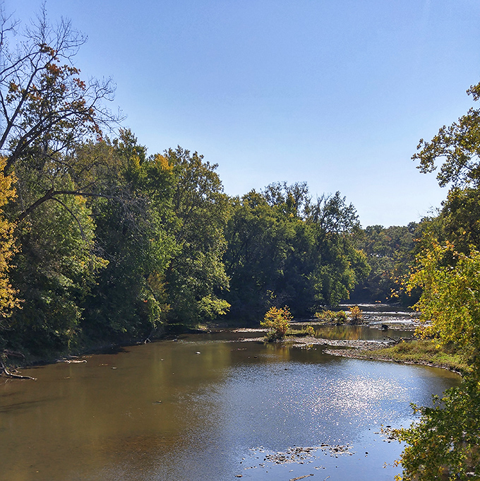 Beyond the wooden beams lies nature's masterpiece&mdash;the Grand River flowing peacefully beneath blue skies, creating a perfect Ohio postcard moment. 