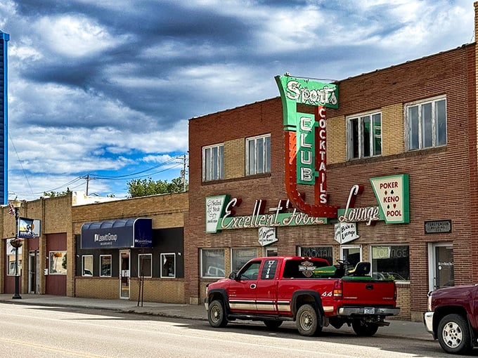 The Sports Club neon sign glows with mid-century promise &ndash; a beacon of local flavor where stories flow as freely as the drinks.