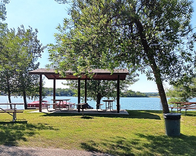 Picnic perfection with a view! These shaded tables offer front-row seats to nature's best show—sparkling water and swaying trees.
