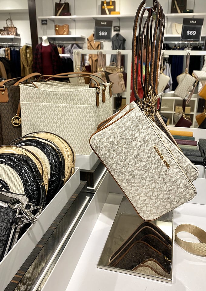 Designer handbags that whisper "luxury" without screaming "bankruptcy." Michael Kors wristlets and totes displayed like the treasures they are.