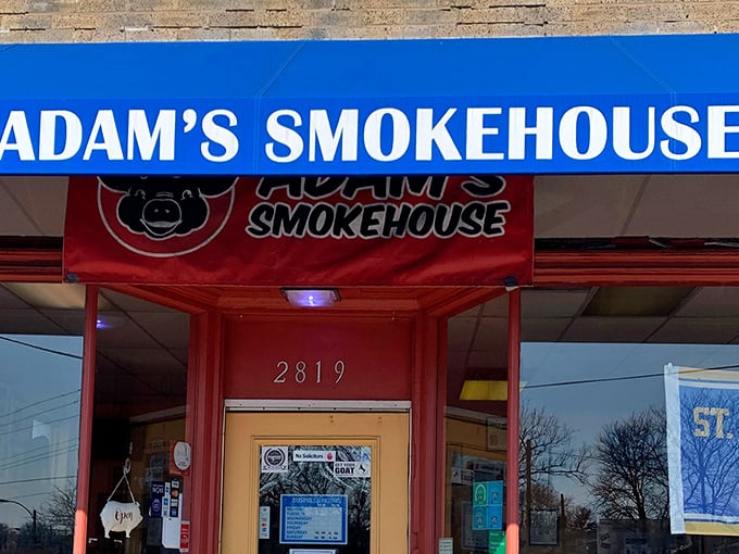 Adam's Smokehouse announces itself with that cheerful blue awning. The cartoon pig knows what you're in for—pork paradise awaits inside!