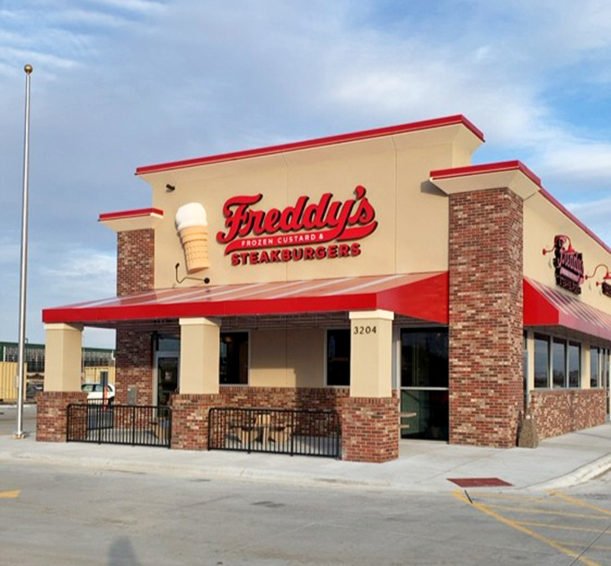 Freddy's classic red and cream facade stands proud, that ice cream cone sign a sweet promise of what comes after your hot dog.