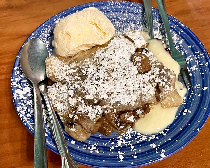Golden apple strudel draped in powdered sugar, accompanied by vanilla ice cream and sauce&mdash;this is what dessert dreams look like.