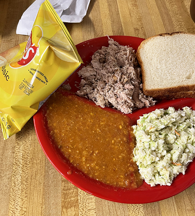 Georgia barbecue perfection on a red plate: tender chopped pork, Brunswick stew that could make a vegetarian weep, and coleslaw that knows its supporting role.