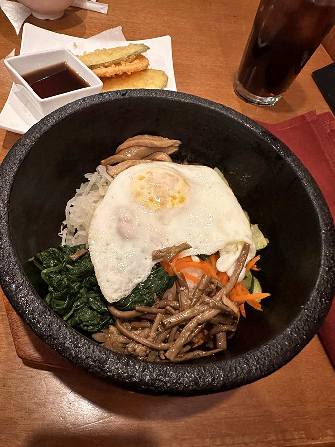 Bibimbap perfection in a sizzling stone bowl &ndash; where crispy rice meets savory vegetables and that glorious runny egg. The sound alone is worth the visit.