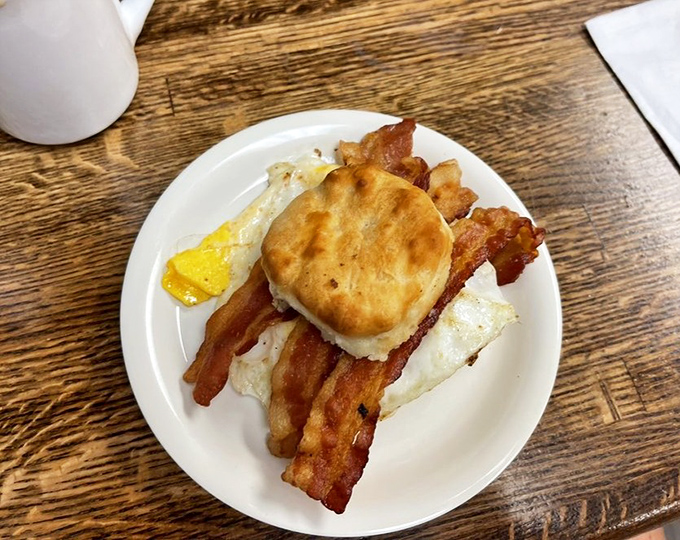 Breakfast architecture at its finest&mdash;a golden biscuit crowning crispy bacon and eggs, no blueprint needed for this perfect morning foundation.