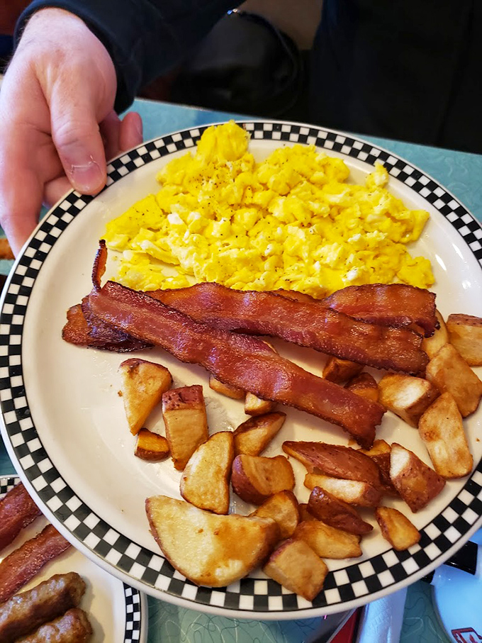 Breakfast perfection on a plate: golden scrambled eggs, crispy bacon, and home fries that could make a potato proud.