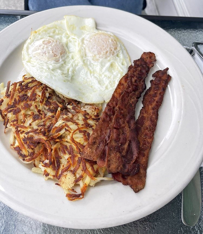 Breakfast perfection on a plate: crispy hash browns with that golden exterior, eggs with properly set whites and runny yolks, and bacon that's achieved the holy grail of textures.