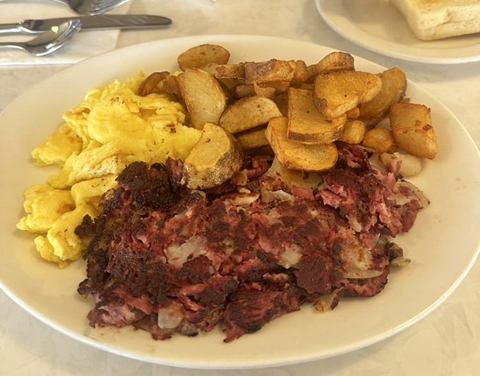 Behold the holy trinity of breakfast: perfectly scrambled eggs, home fries with that ideal crisp-tender balance, and corned beef hash that would make your grandmother weep with joy.