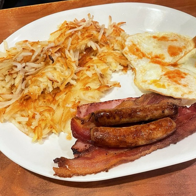 The breakfast trinity: perfectly crispy hash browns, eggs with just-right runny yolks, and sausage links that snap when you bite them. Morning salvation on a plate.