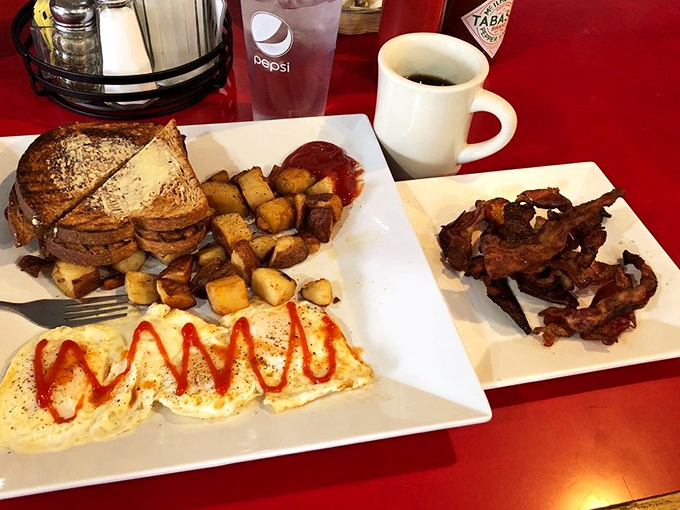 This breakfast plate is what morning dreams are made of &ndash; perfectly golden home fries, eggs with a sassy sriracha drizzle, and bacon that deserves its own fan club.