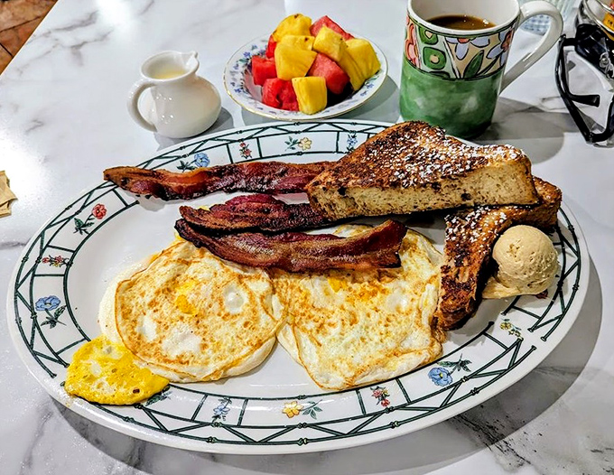 Breakfast perfection on a floral-rimmed plate &ndash; eggs, bacon, and French toast forming a holy trinity of morning satisfaction.
