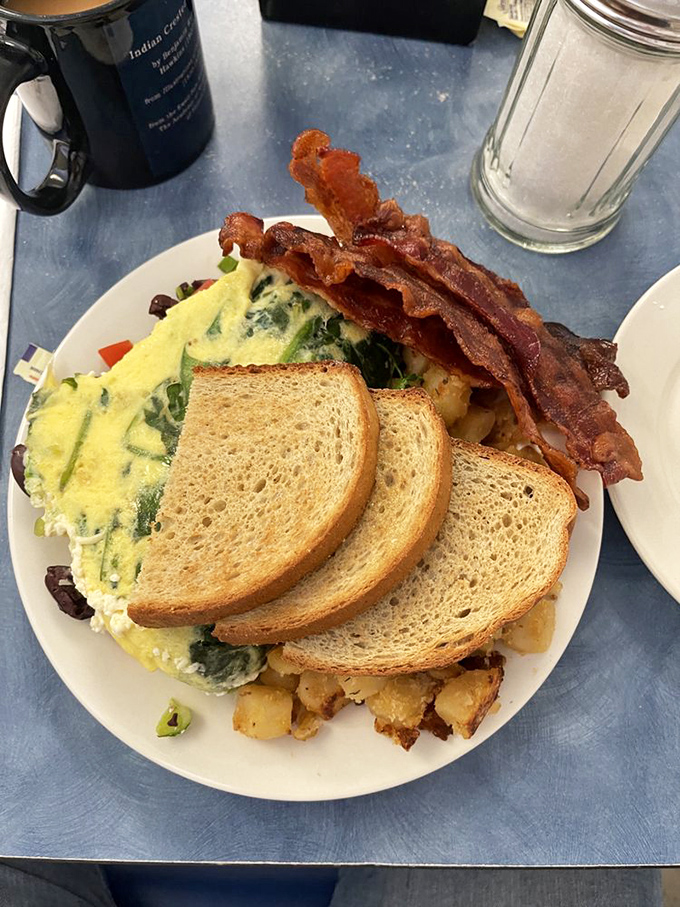 Spinach omelet perfection meets crispy bacon and golden toast. This isn't just breakfast &ndash; it's the reason alarm clocks were invented.