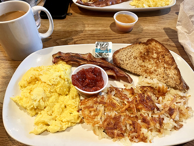 Breakfast perfection on a plate: fluffy scrambled eggs, crispy bacon, golden hash browns, and toast that's achieved that elusive perfect shade of brown.