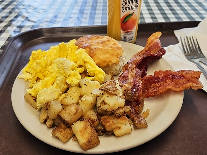 Behold the breakfast trifecta: eggs, bacon, and biscuit living in perfect harmony alongside those gloriously golden home fries.