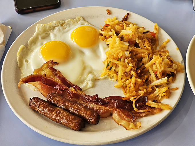 Breakfast perfection on a plate: sunny-side up eggs with that perfect runny yolk, crispy bacon, and hash browns that deserve their own fan club.