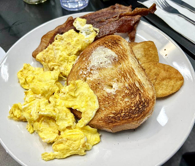 Breakfast simplicity at its finest: golden scrambled eggs, perfectly toasted bread, and bacon that makes you question why you ever bothered with cereal.