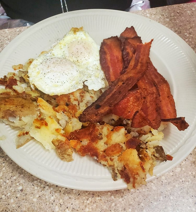 Breakfast nirvana achieved: crispy-edged eggs, hash browns with that perfect golden crust, and bacon that makes you question why anyone would ever choose turkey bacon.