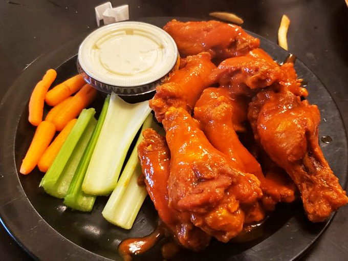 Buffalo wing perfection: glistening with sauce, accompanied by cooling celery, carrots, and blue cheese. A holy trinity of flavor that changed America forever.