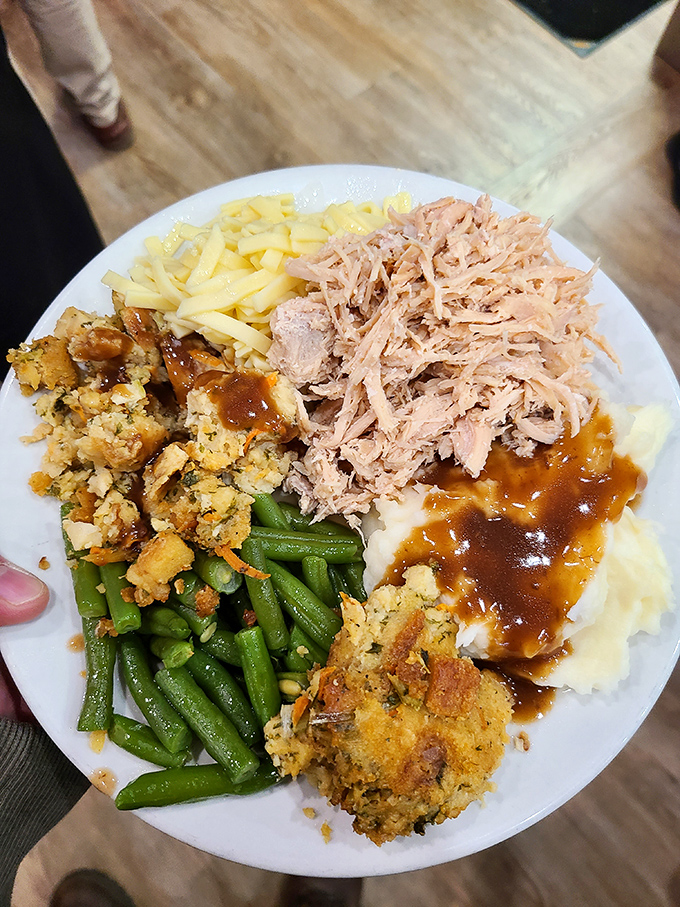 This isn't just a plate—it's a masterpiece of comfort food architecture with perfectly stacked mashed potatoes, green beans, and pulled turkey that demands to be devoured.