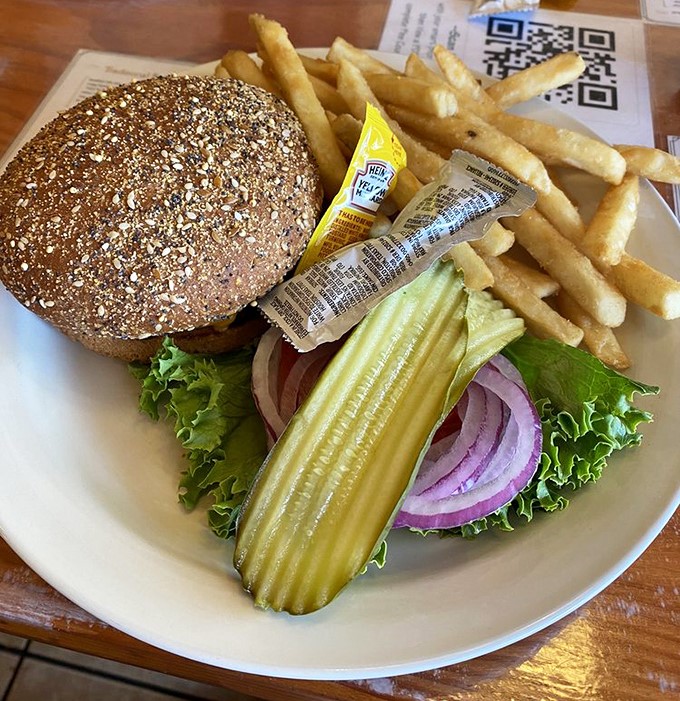 This isn't just a burger&mdash;it's an architectural masterpiece of pickle, onion, and lettuce on a multi-grain throne. The fries aren't sidekicks; they're co-stars in this delicious production