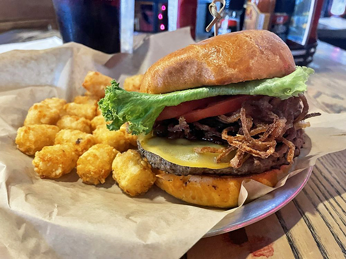 Behold the burger in its natural habitat &ndash; a towering masterpiece of beef, fresh toppings, and those addictive tater tots standing guard.