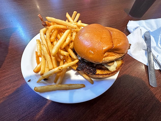 Behold the humble burger in its natural habitat &ndash; perfectly seared, properly dressed, and flanked by a golden army of crispy fries.
