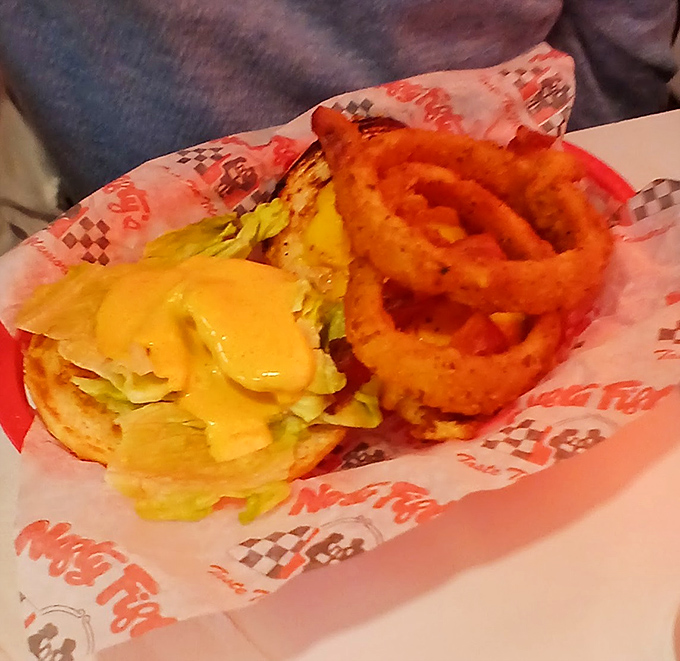 This isn't just a burger&mdash;it's architecture with cheese. The golden onion rings standing guard beside it aren't accessories, they're necessities.