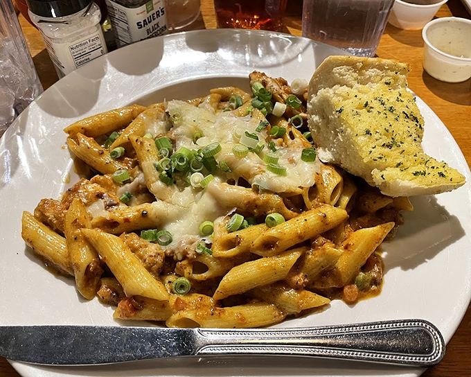 The star of the show: Cajun pasta with perfectly cooked penne, sprinkled with green onions and served with garlic bread that demands to be devoured.